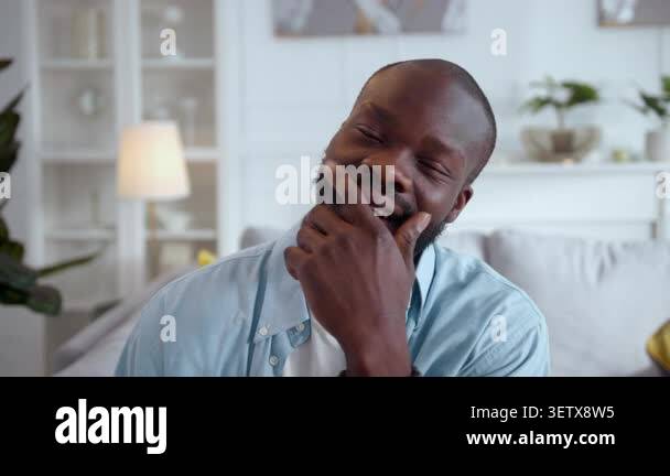 In a cozy living room, a man contemplatively sits on a couch ...