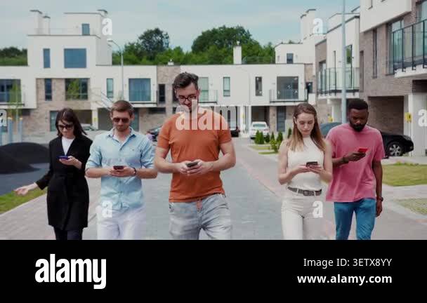A diverse group of people is walking leisurely down a busy street while ...