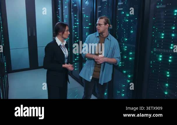 In a modern data center, a man and woman discuss among hightech servers ...