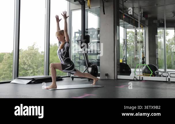 Young flexible woman doing a crescent lunge and plank pose sequence on ...
