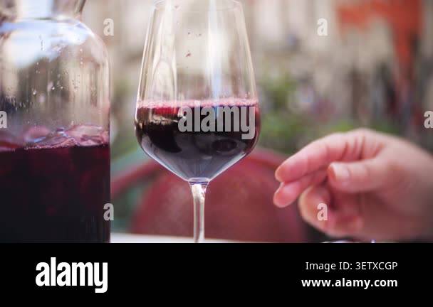 Hand holding a glass of refreshing red sangria wine. Close up view of ...