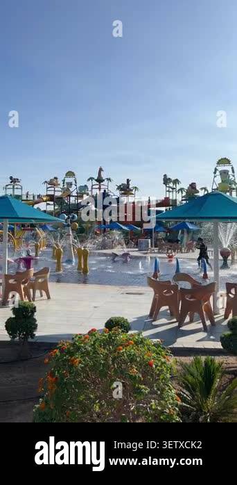 People enjoying sunny outdoor water park with colorful slides on June ...