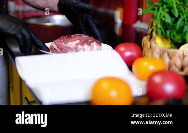 Chef in black gloves seasons, sears and bastes a ribeye steak with ...