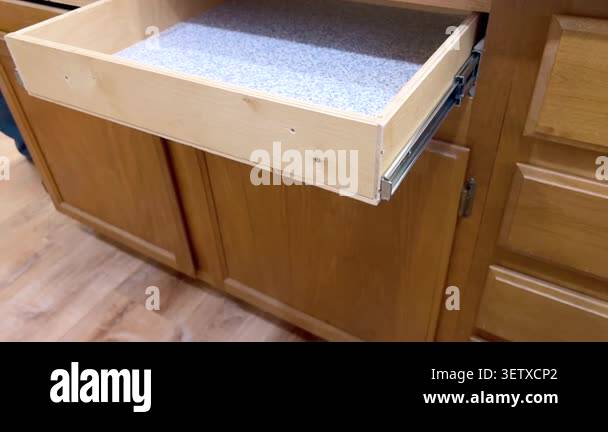 The video shows a hand pulling open a wooden kitchen drawer lined with ...