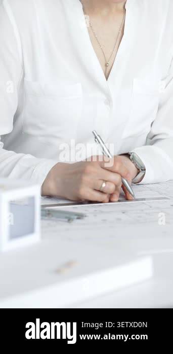Female architect or engineer carefully reviewing and drawing on ...