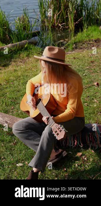 Blonde woman playing string guitar outdoors in autumn forest. Concept ...