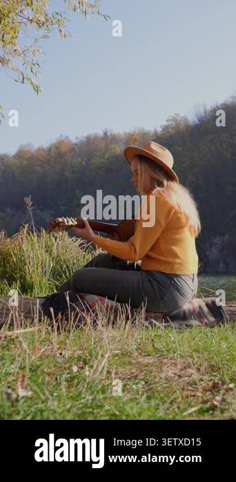 Beautiful blonde girl playing acoustic guitar and singing relaxing ...