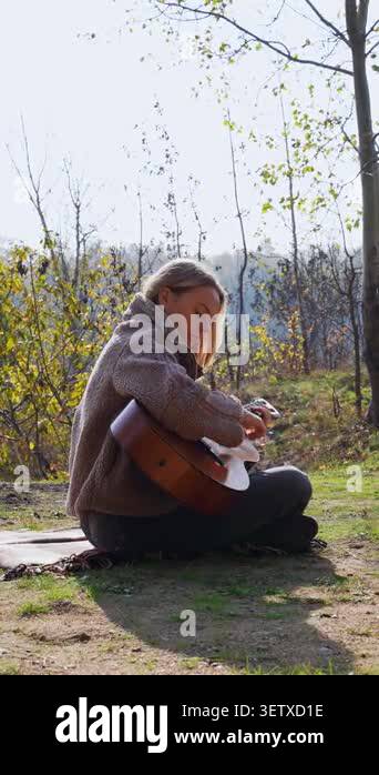 Beautiful blonde girl playing acoustic guitar and singing relaxing ...