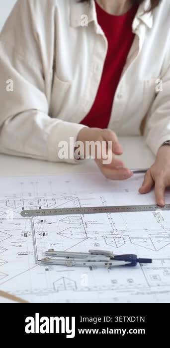 Woman architect drafting detailed blueprints at desk with ruler and pen ...