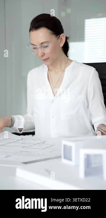 Female architect or engineer carefully reviewing and drawing on ...