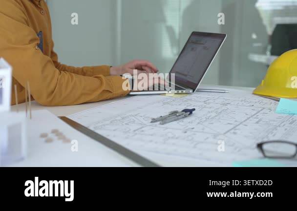 Architect working on construction plans using a laptop, drafting new ...