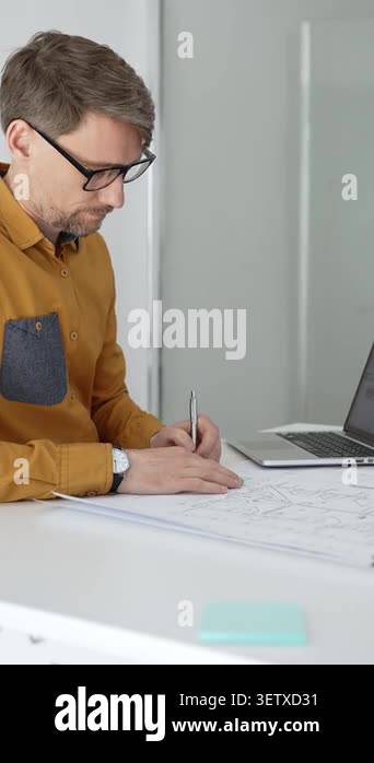 Architect working on construction plans using a laptop, drafting new ...