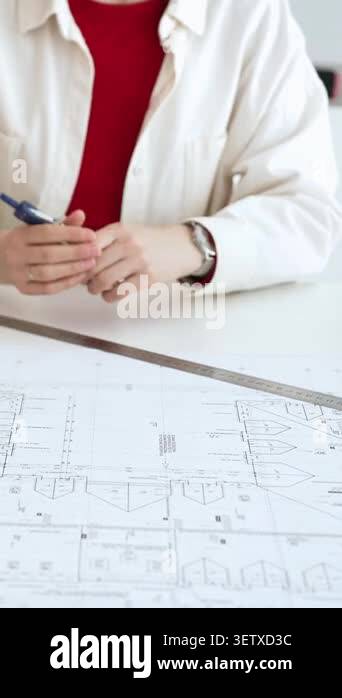 Woman architect drafting detailed blueprints at desk with ruler and pen ...