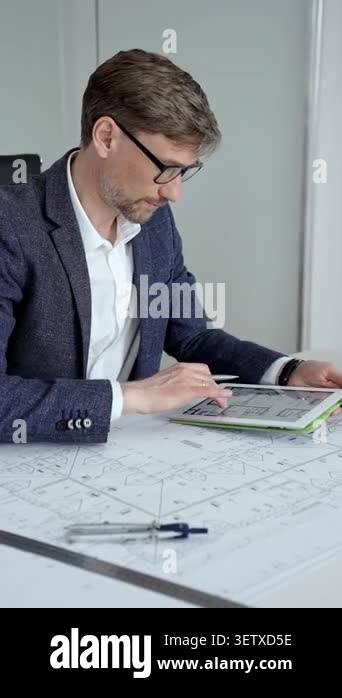 Male architect reviewing building blueprints and interacting with a ...