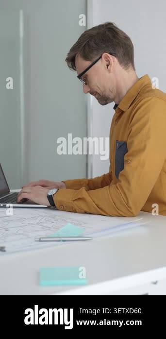 Architect working on construction plans using a laptop, drafting new ...