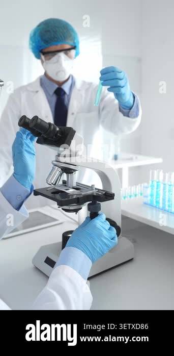 Two scientists in lab coats, face masks, and protective glasses ...