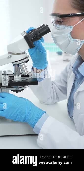 Female scientist wearing blue protective gear analyzing test samples ...
