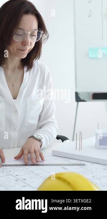 Female architect in office carefully drawing blueprint for new ...