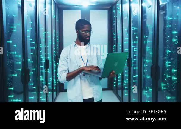 An IT professional diligently works in a modern server room, managing ...