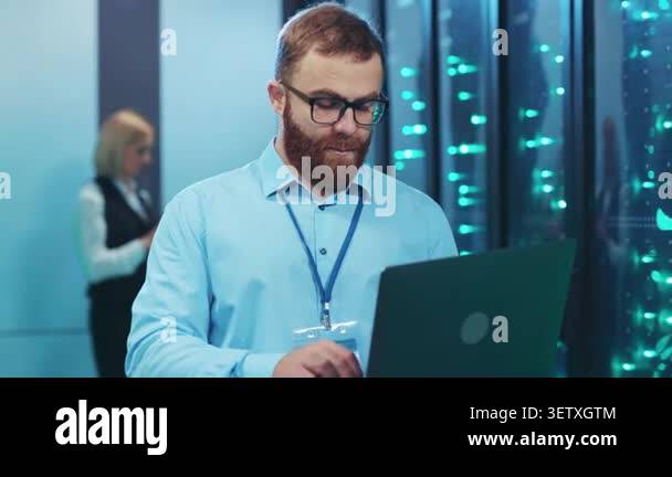 In a bustling server room, a bearded man engages intensely with his ...