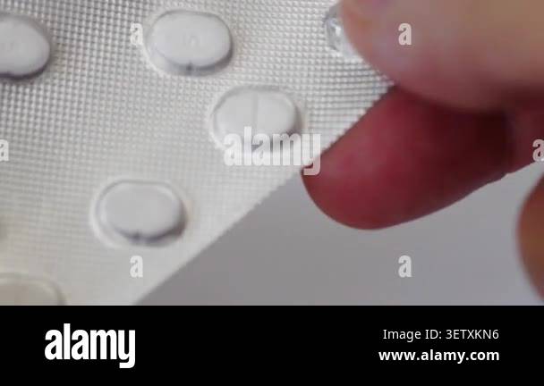 A macro close up of hands popping open and taking a medicine tablet ...