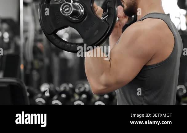 Muscular athlete performing barbell bicep curls during strength ...