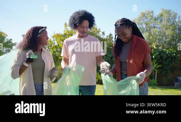 African American friends volunteering, organizing green trash bags ...