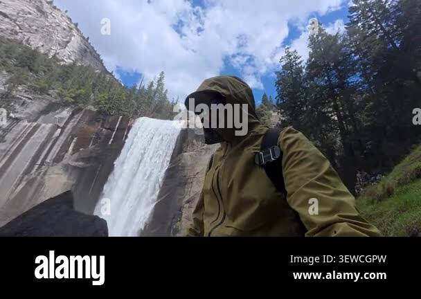 Young hiker in a waterproof jacket recording a selfie video while ...
