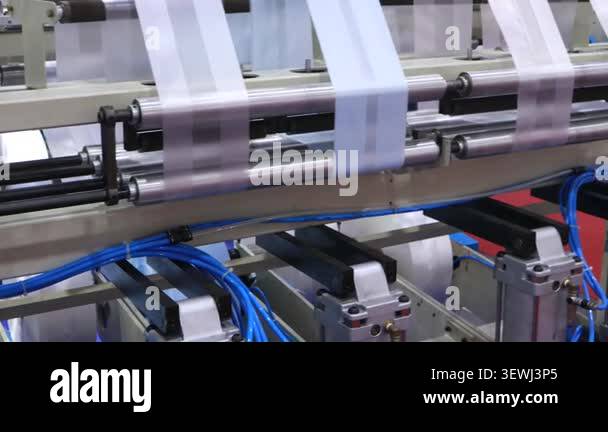 Plastic film rolling on industrial machine rollers close up., Automated ...