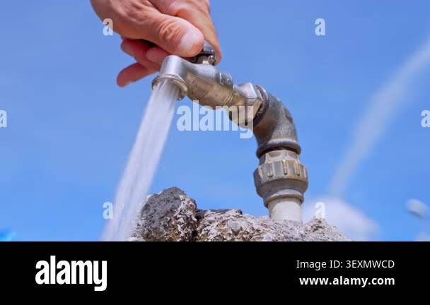 Human hand filling a clear plastic bottle with fresh water from a metal ...