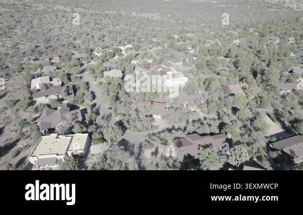 An elevated drone shot captures a calm residential area with tree-lined ...