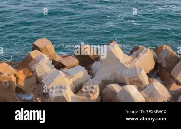 A cluster of large concrete tetrapod breakwater block stacked along a ...