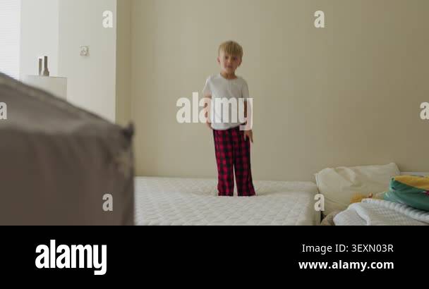 toddler jumping on bed in bedroom, energetic preschool boy in plaid ...