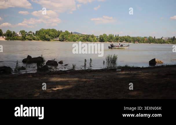 Wide shot of a fisherman sitting in a small motorboat on a wide river ...