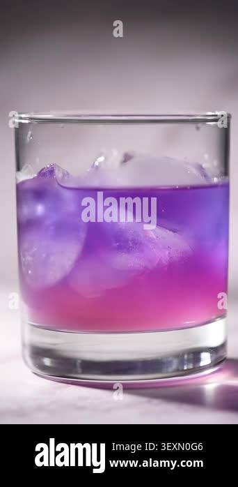 A vertical close-up of butterfly pea tea served with ice in a clear ...
