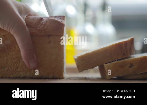 Hand slicing bread with knife, cutting thick pieces from a loaf ...