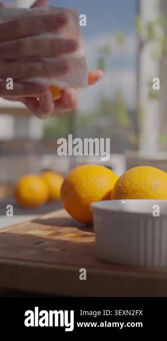 Hand wipes orange with paper towel on kitchen counter with fresh ...