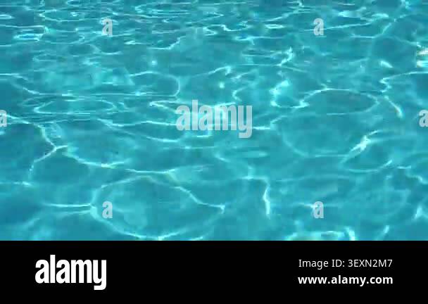 Shining azure swimming pool water with sunbeams creating rippled light ...