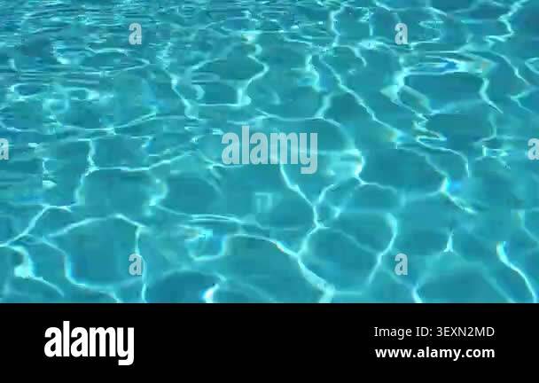 Shining azure swimming pool water with sunbeams creating rippled light ...