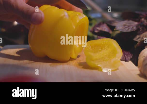 A mans hand slices fresh vegetables for a salad on a wooden cutting ...