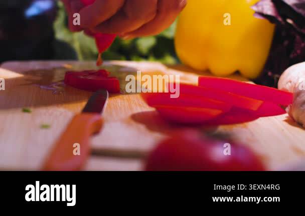A mans hand slices fresh vegetables for a salad on a wooden cutting ...