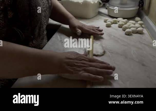 Medium overhead shot of a woman hands rolling out and stacking thin ...