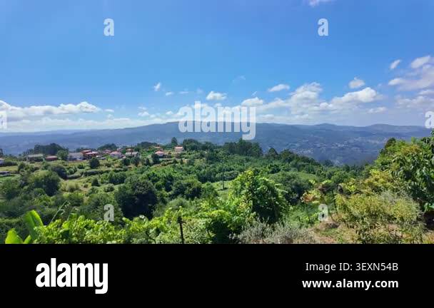 A sweeping vista overlooks a verdant hillside with a small village ...