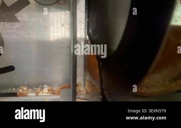 A top-down view shows a mechanical slicer cutting a loaf of artisan ...