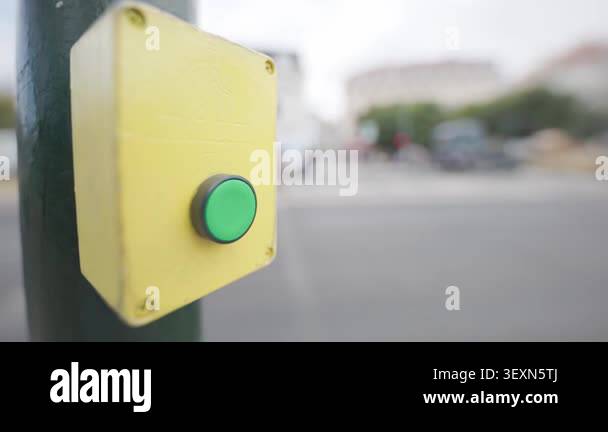 Close-up of a pedestrian call button with blurred city traffic moving ...