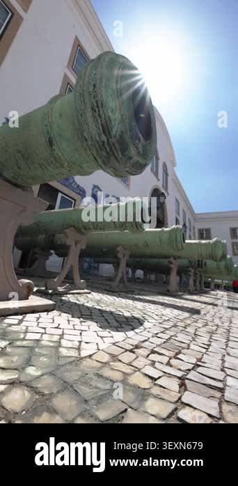 Sun flaring over a row of old, weathered bronze cannons outside a ...