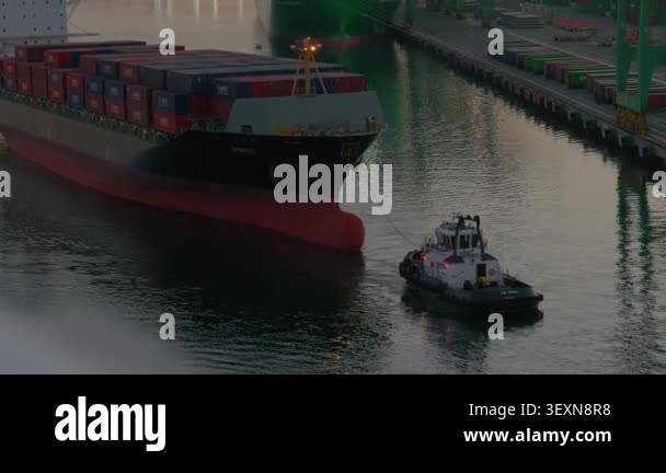 Tugboat towing large cargo container ship in harbor channel Stock Video ...