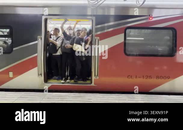Packed commuter train passengers standing at an open train door during ...