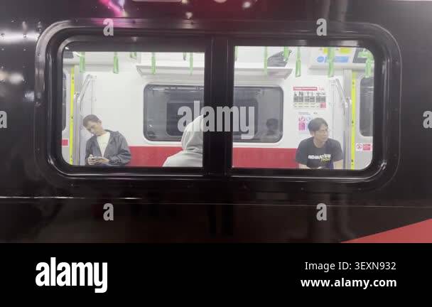Nighttime view of a passenger seated inside a commuter train carriage ...