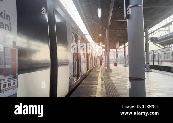 Silhouetted train driver walking along a railway platform during sunset ...